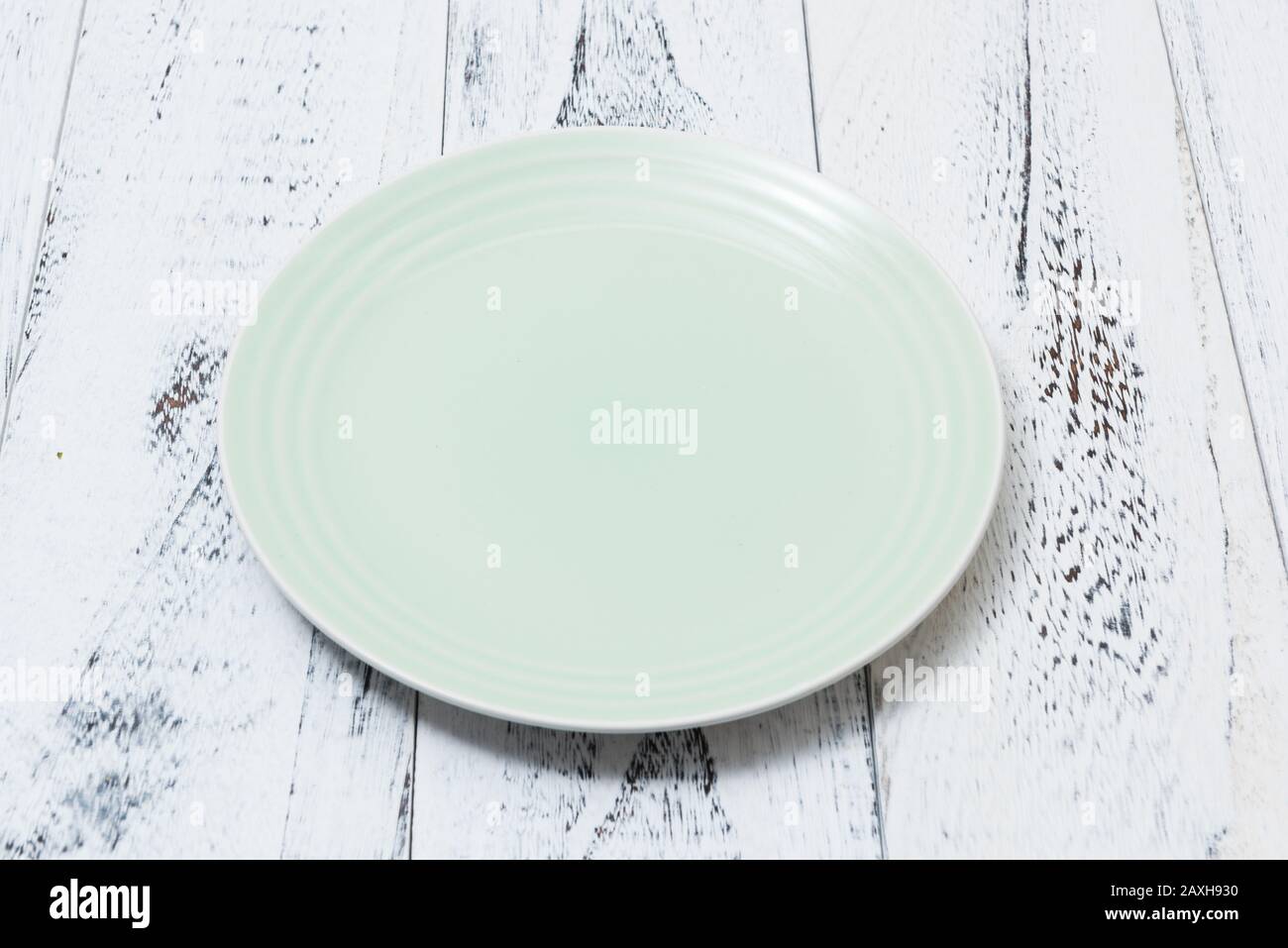 Green Round Plate on white abstract scraped wooden table background ...