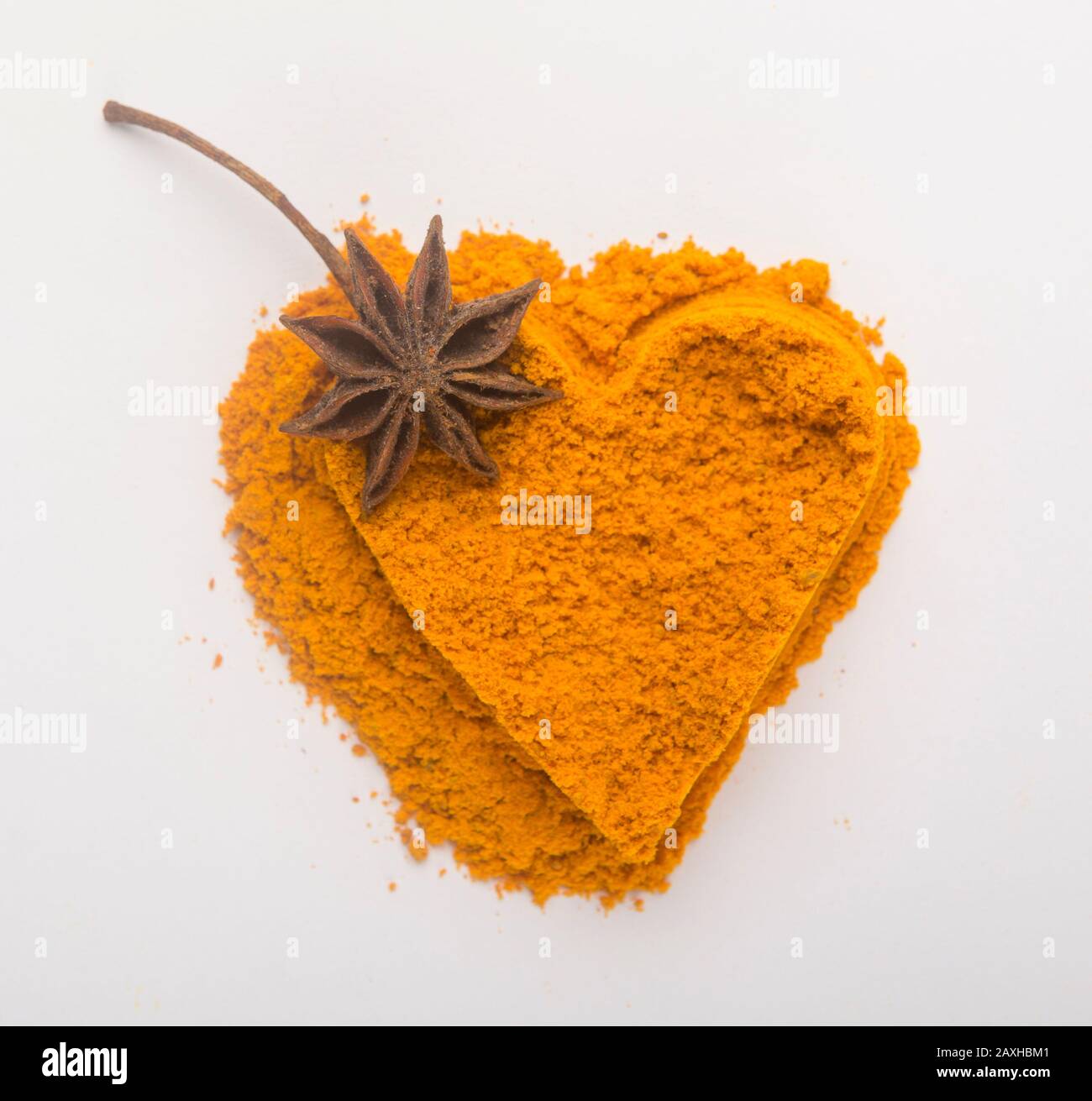 Heart of turmeric powder decorated with anise on white Stock Photo - Alamy