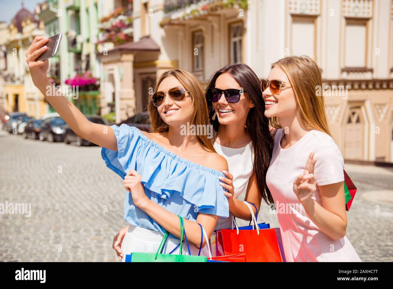 Three happy pretty shoppers making photo on smartphone Stock Photo - Alamy