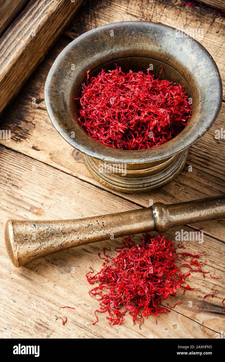 Raw organic red saffron spice on wooden background.Vintage metal mortar ...