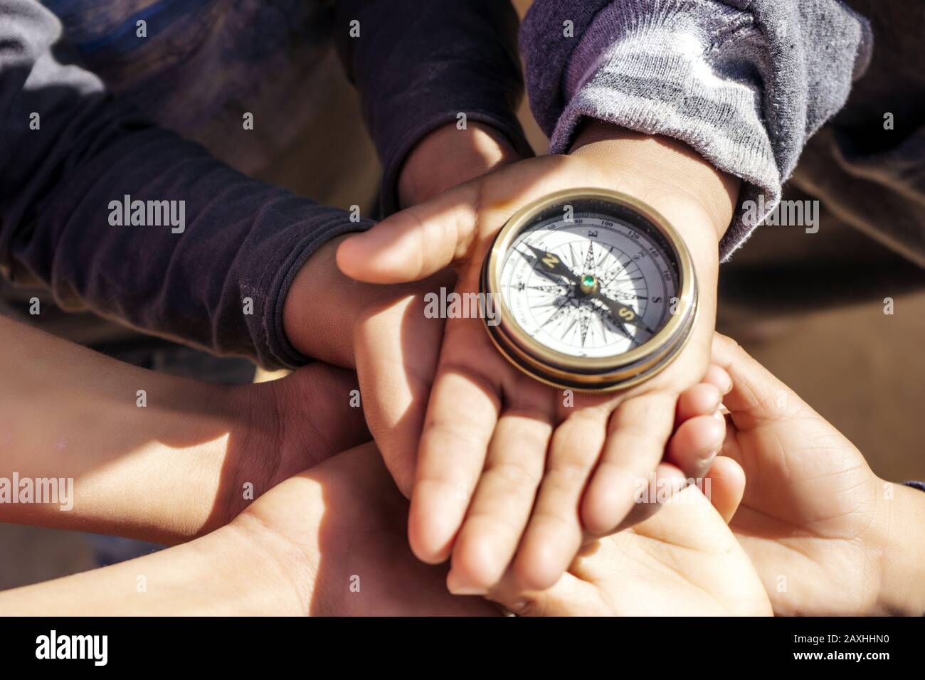 Group of children's hands holding a compass - teamwork concept Stock ...