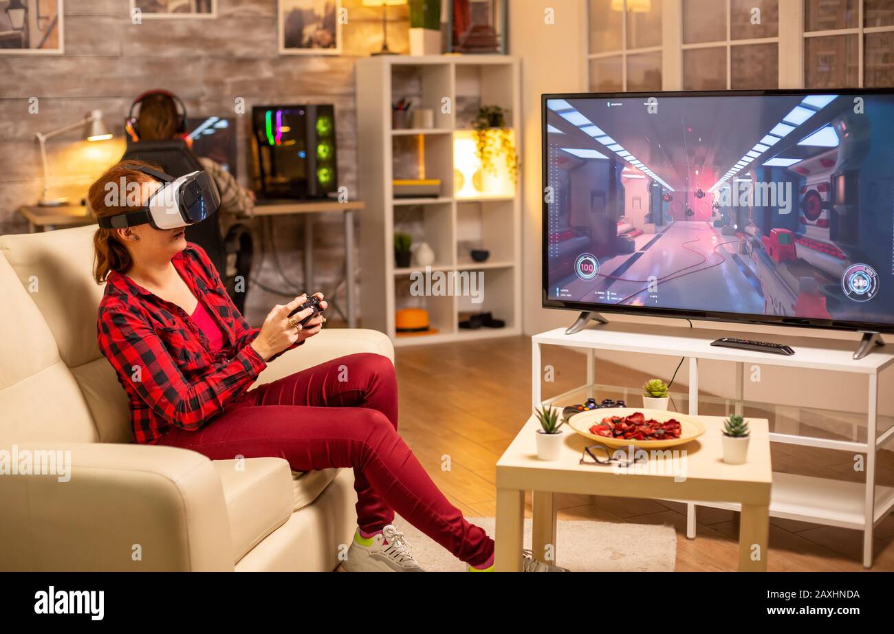 Woman gamer playing video games using a VR headset late at night in the ...