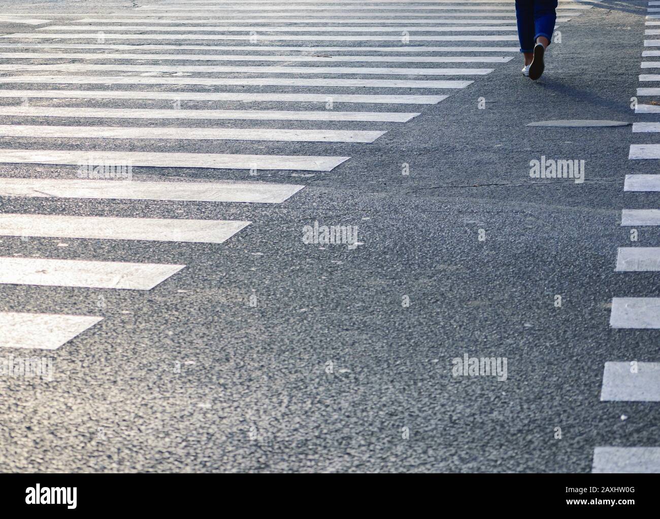 Beautiful shot of the zebra crossing on the road with female walking ...