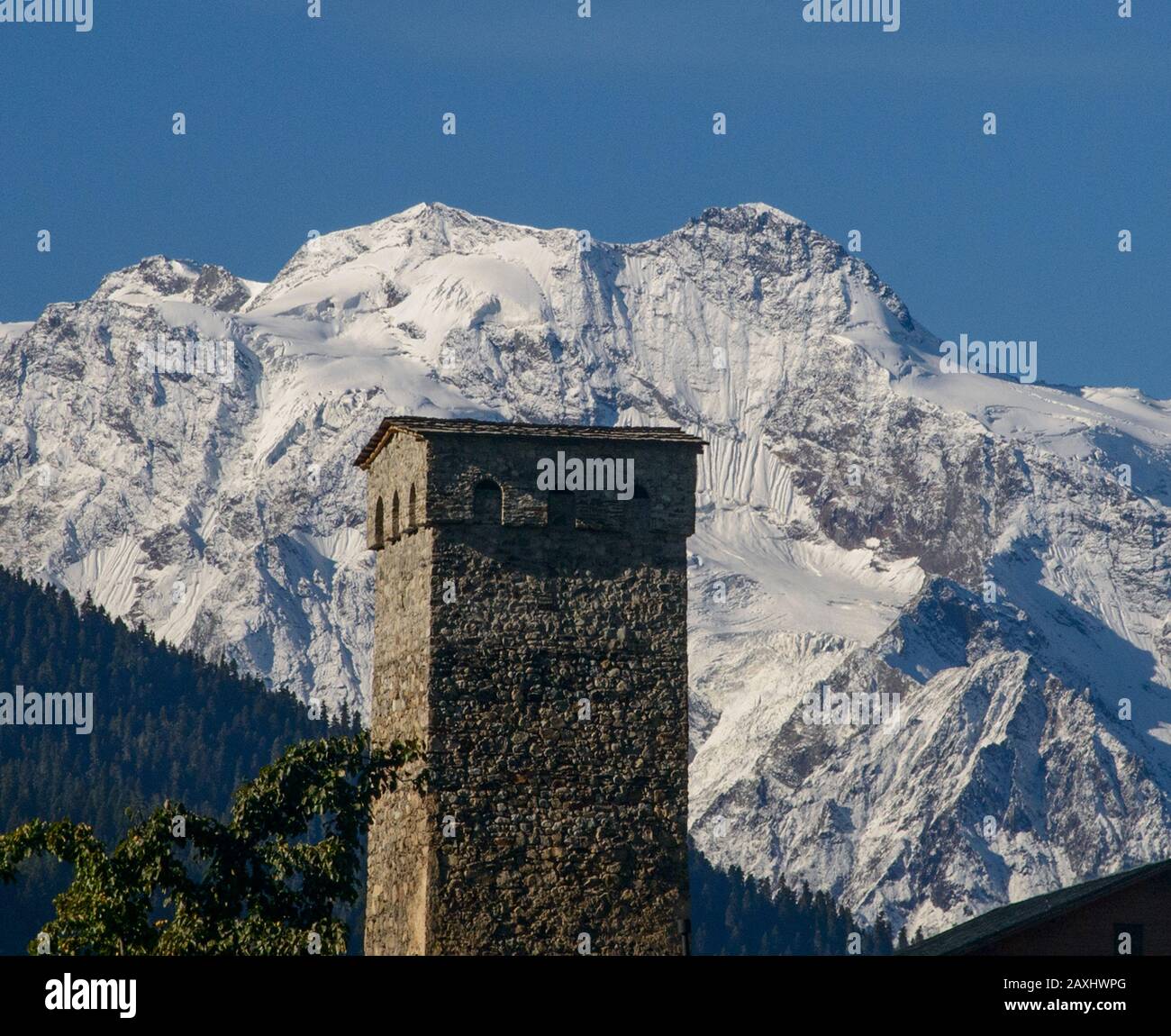 Svaneti towers against snow covered mount. Blue sky contrasts ...