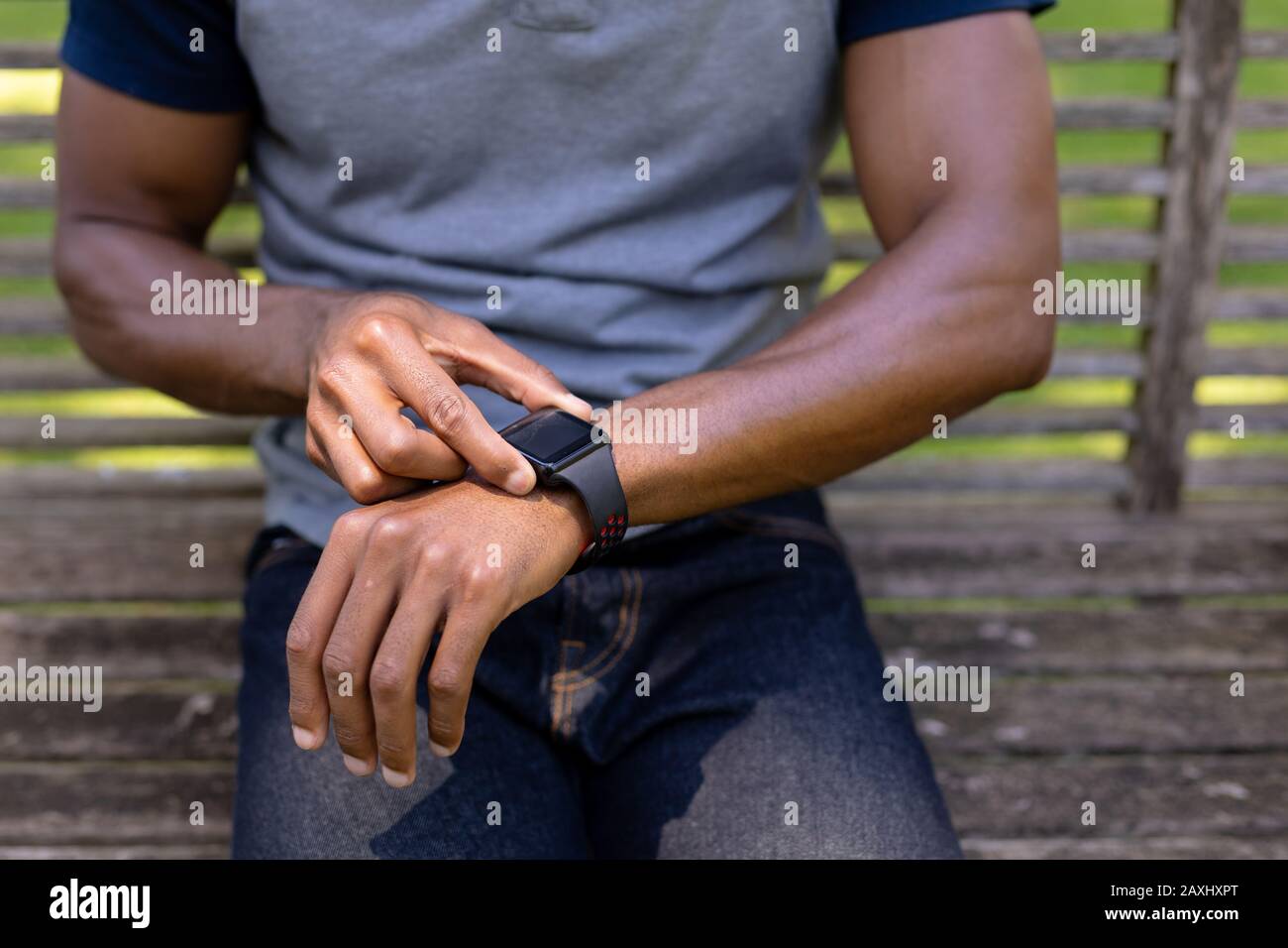 Young man sitting on a bench and using his smart watch Stock Photo - Alamy