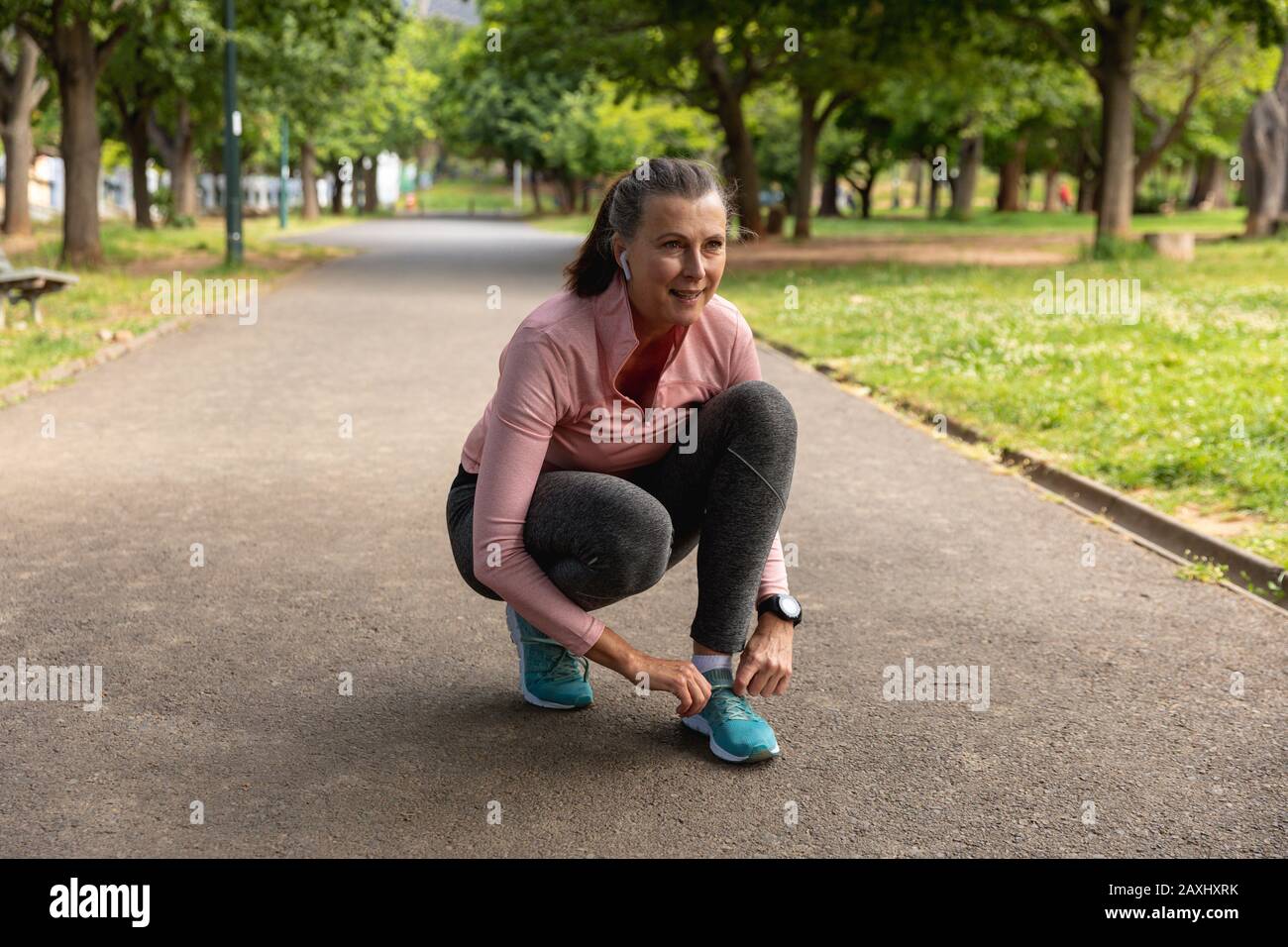 Female jogger tying her shoe laces in the park Stock Photo - Alamy