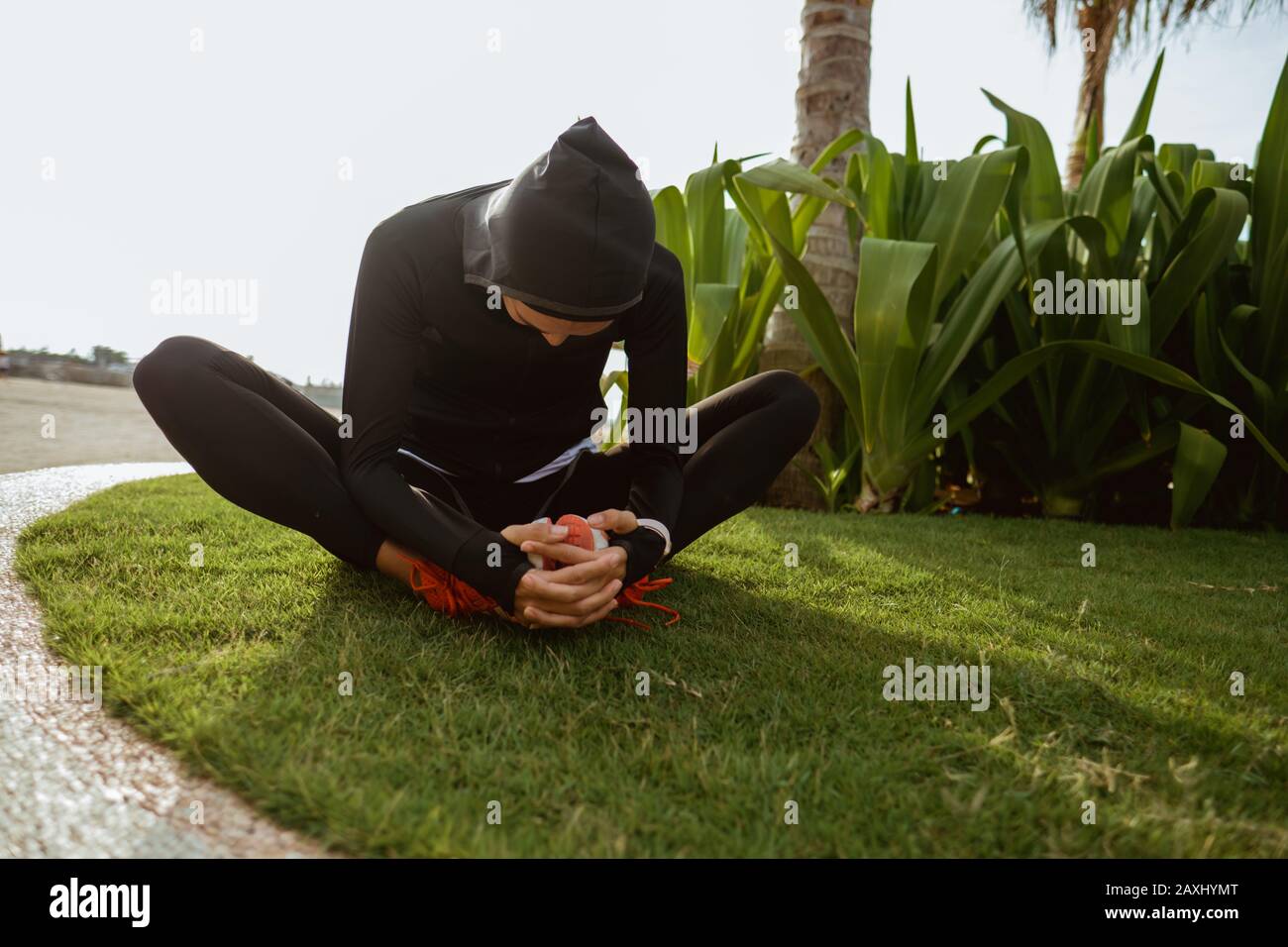 Young fitness muslim woman runner stretching legs before run Stock ...