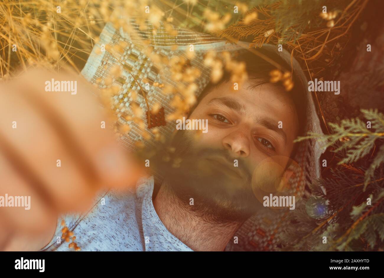 Turkish young man holding a flower or weed in sunlight outside and top ...