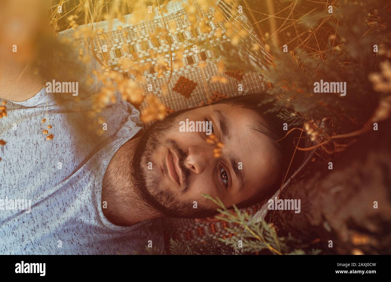 Turkish young man holding a flower or weed in sunlight outside and top ...