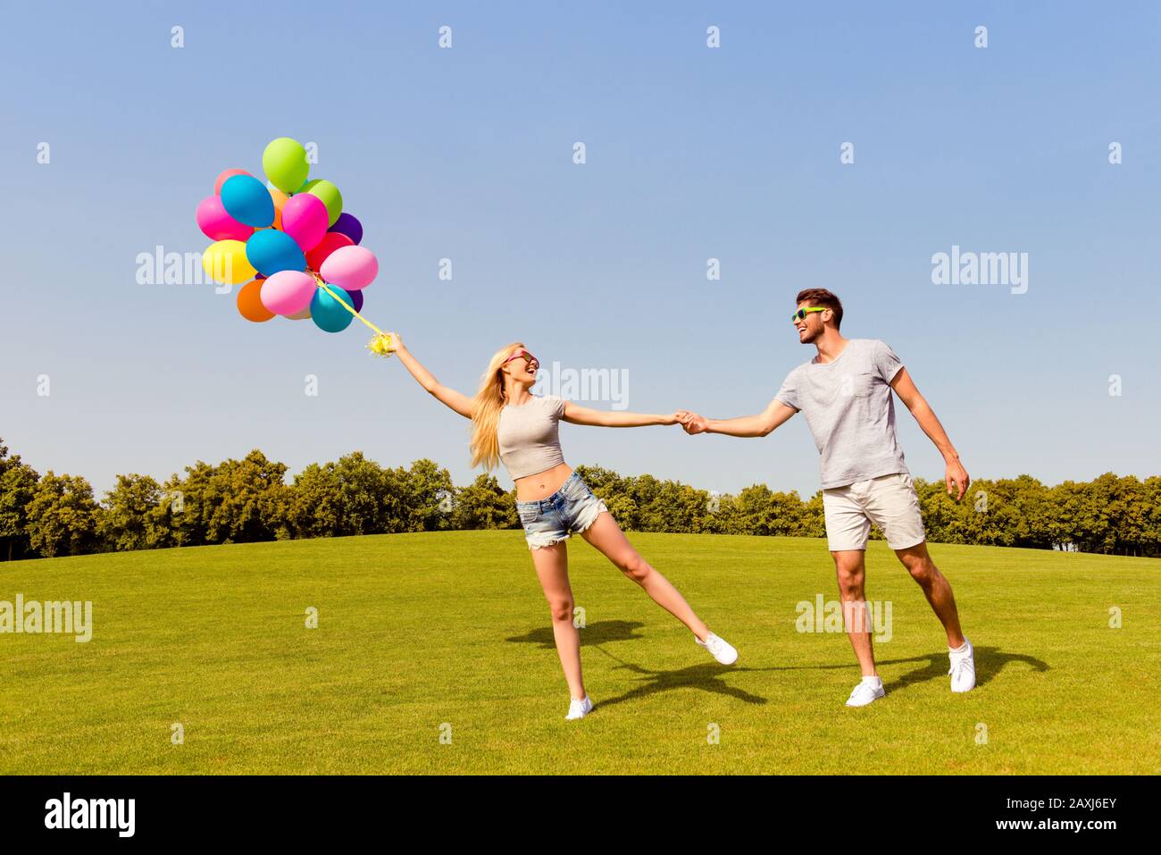 Happy man catching his girlfriend not to fly with balloons Stock Photo ...