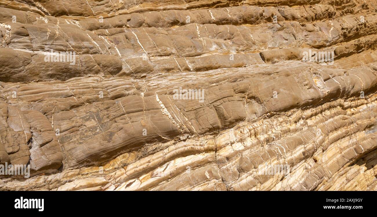 Folded sedimentary rock strata dipping downwards in cliff at Praia dos ...