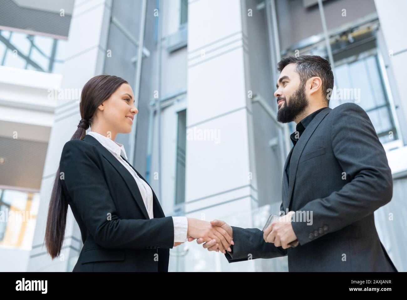 Below view of smiling lady handshaking with new business partner while ...
