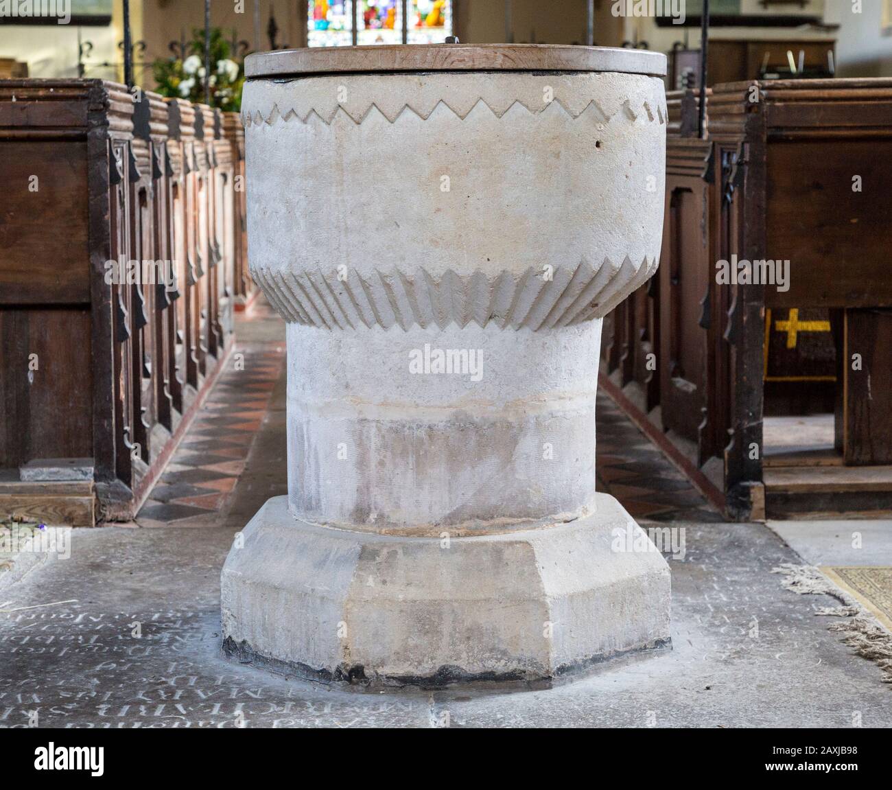 Simply decorated stone 12th century baptismal font inside church at ...