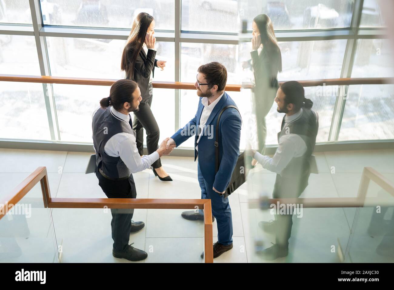 Content businessmen making handshake in corridor of office center, they ...