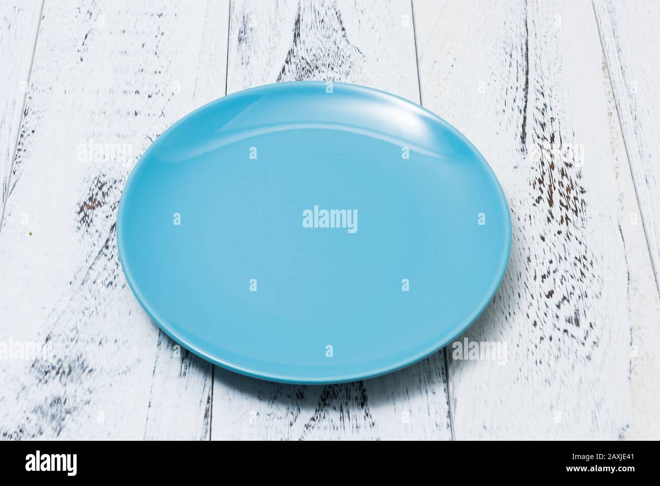 Blue Round Plate on white abstract scraped wooden table background side ...