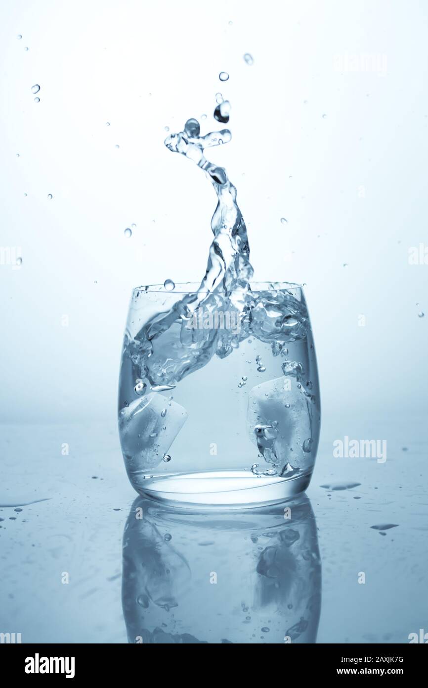 Beautiful splash, ice cube falling into the water, a glass with clean ...