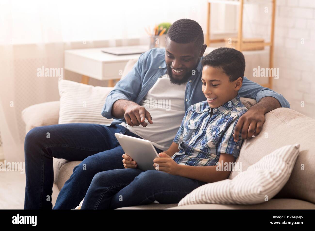 Father and son using digital tablet at home, checking new application ...