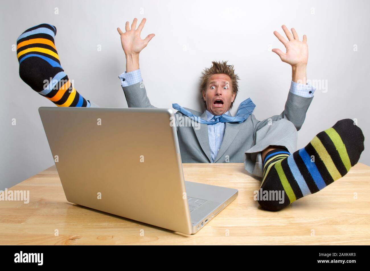 Shocked businessman falling back from the laptop computer on his desk ...