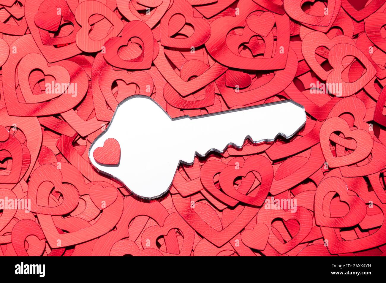 Shiny three dimensional key sitting on a pile of red hearts with ...