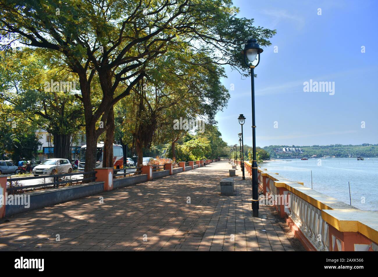 Side walk along the mandovi river in Goa with beautiful trees beside ...