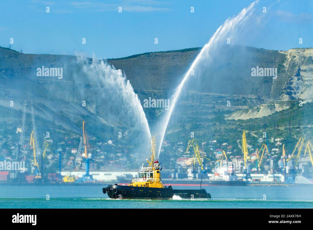 Floating tug boat is spraying jets of water, demonstrating firefighting ...