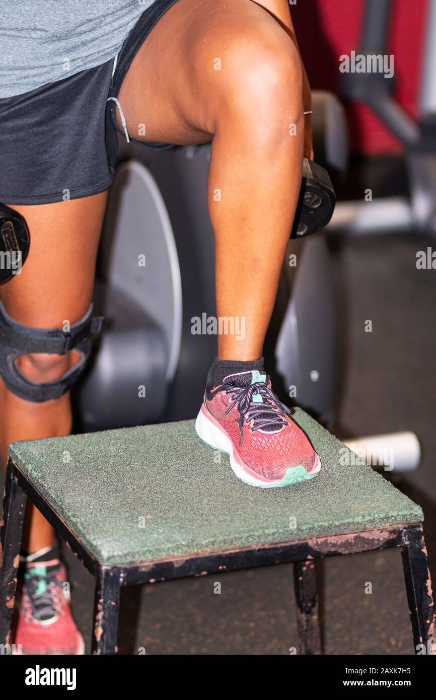 African american athlete with knee brace inside a gym performing step ...