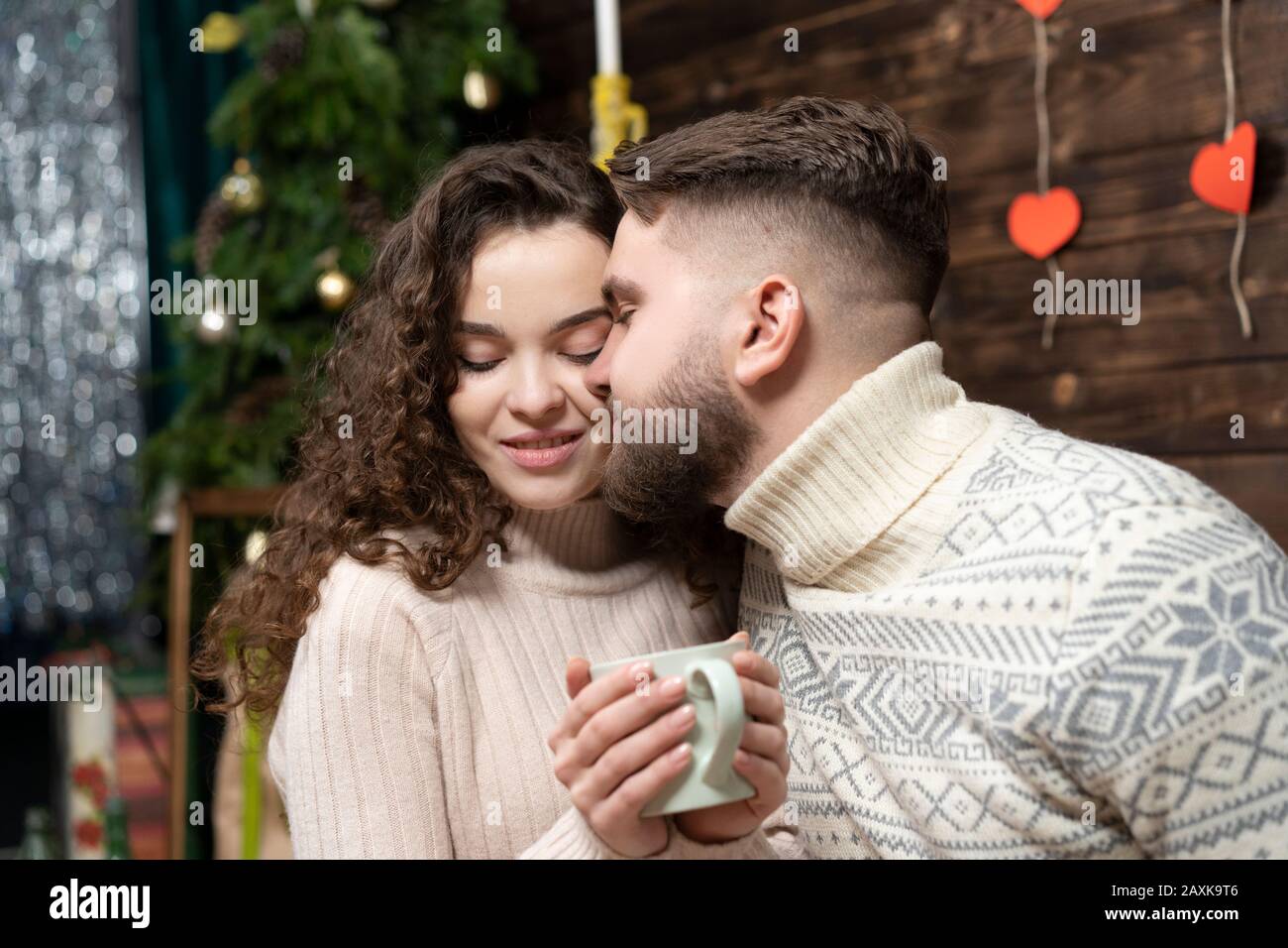 Man kissing woman with cup of tea Stock Photo - Alamy
