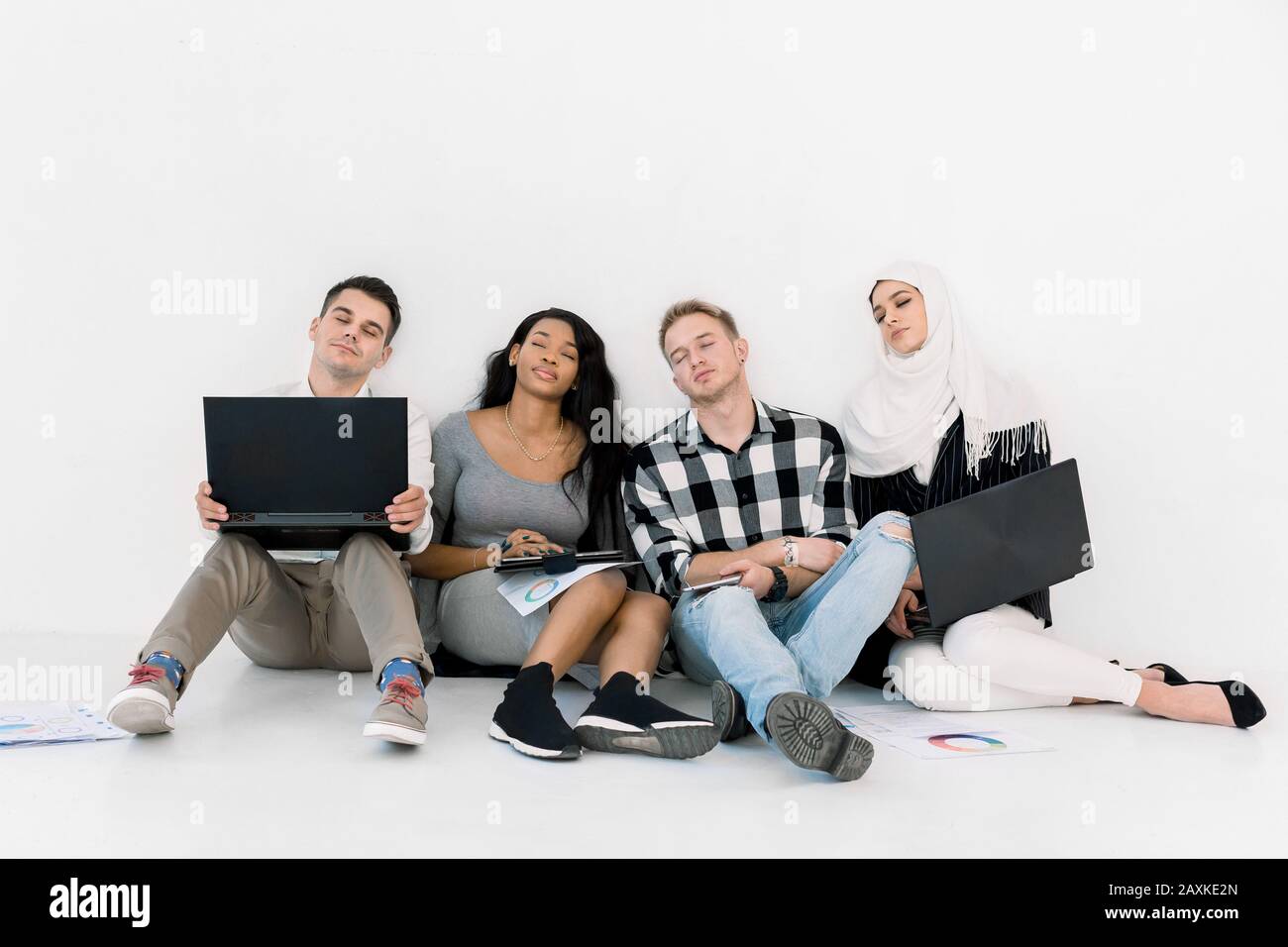 Multiethnic group of four tired students or colleagues falling asleep ...