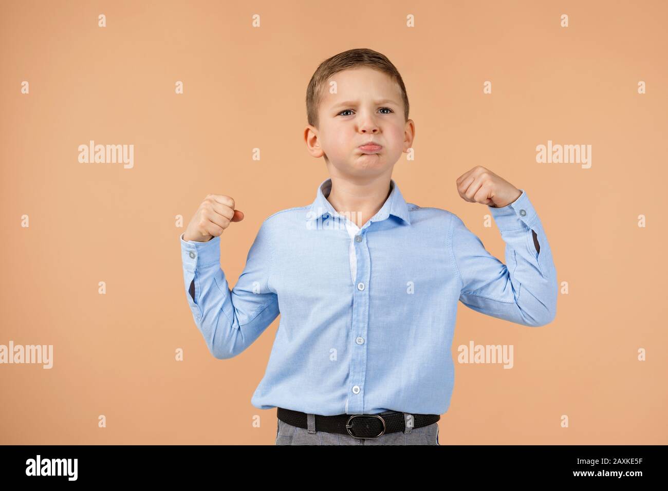 little boy shows his biceps on beige background. child showing his ...