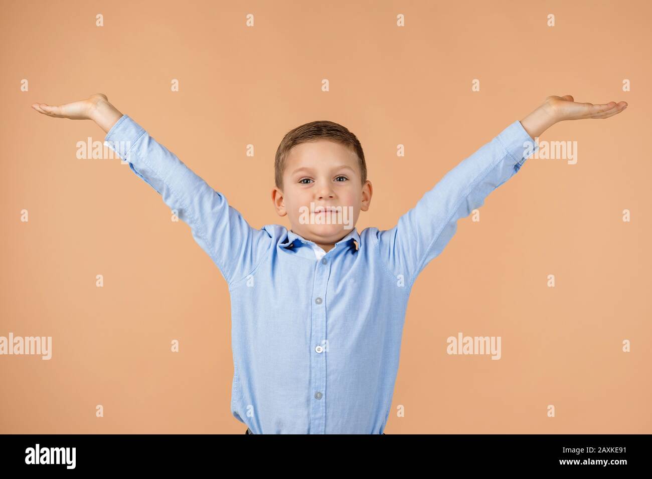 Cute happy smiling little child boy raising her hands up on beige ...