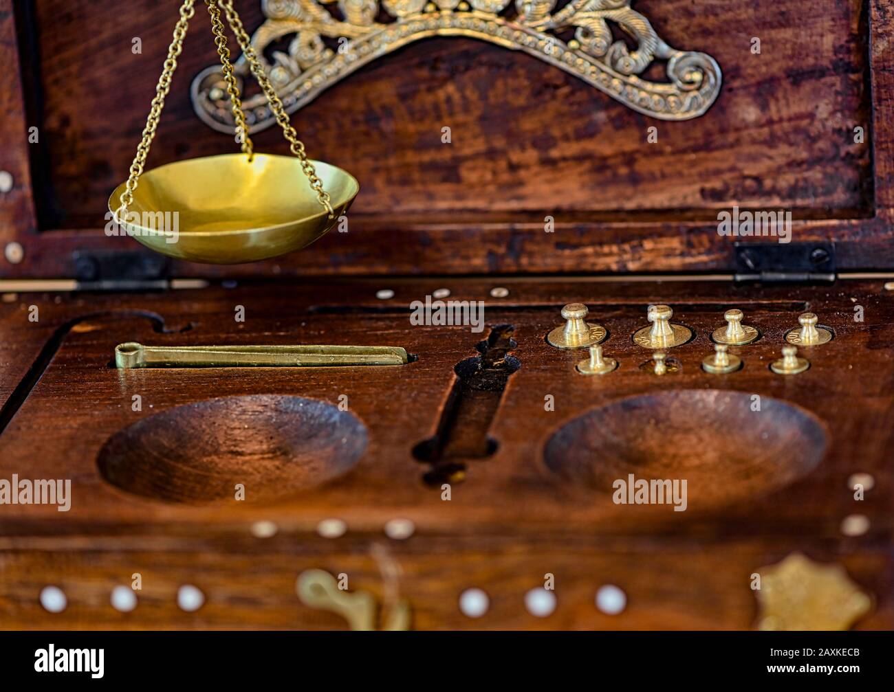 Close-up of an old gold scale with various decorations in a wooden box ...