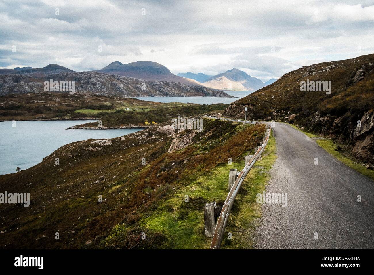 Landscape with rural road cutting through mountains and lochs under a ...