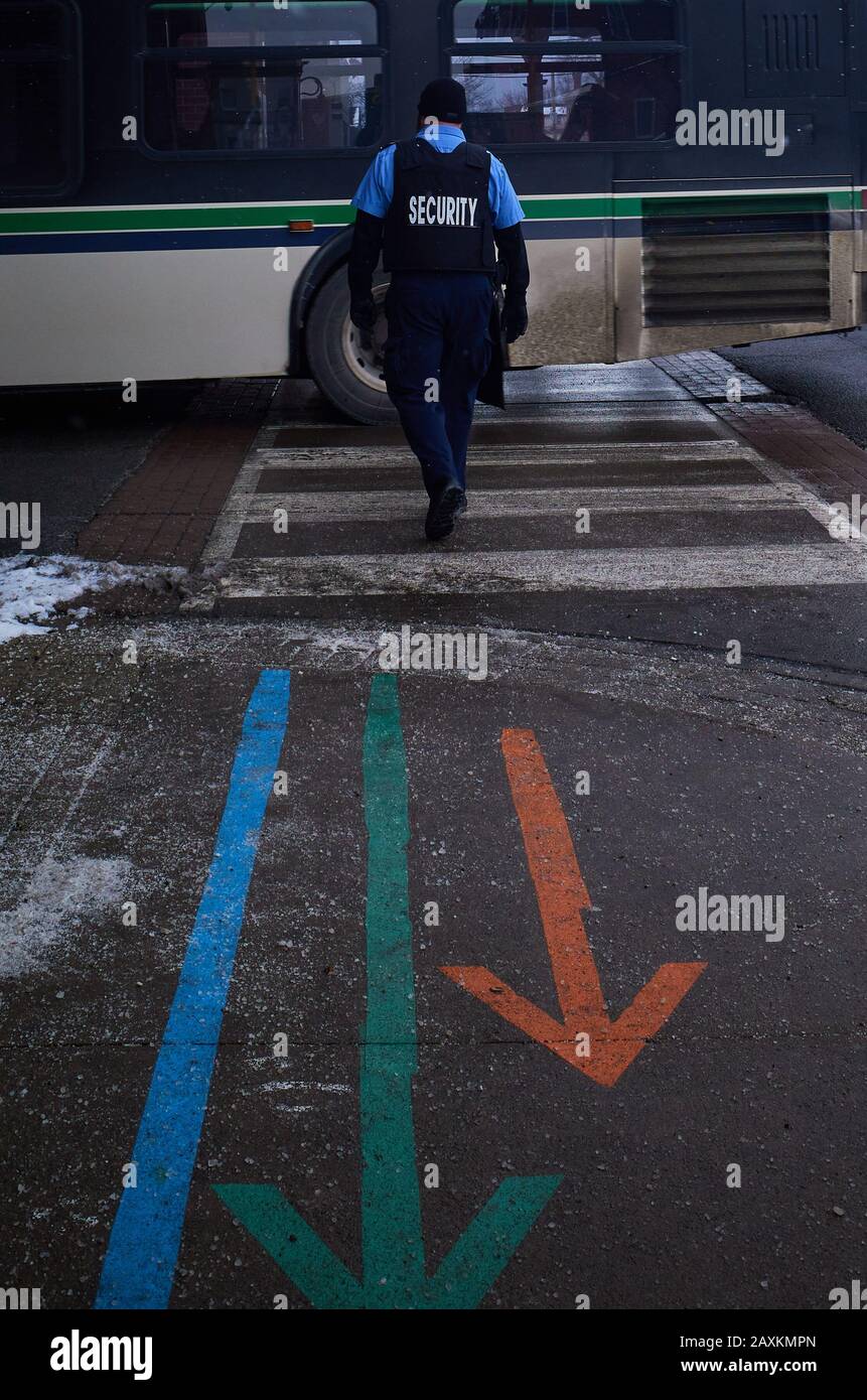 Security guard walks sidewalk with colored directional arrows at bus ...