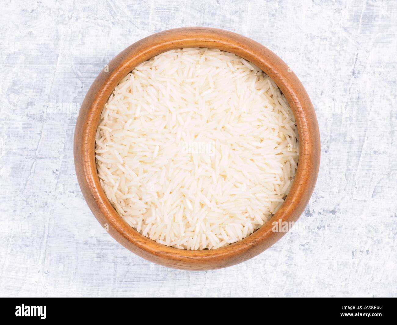 Indian long grain Basmati rice in brown wooden bowl on white concrete ...