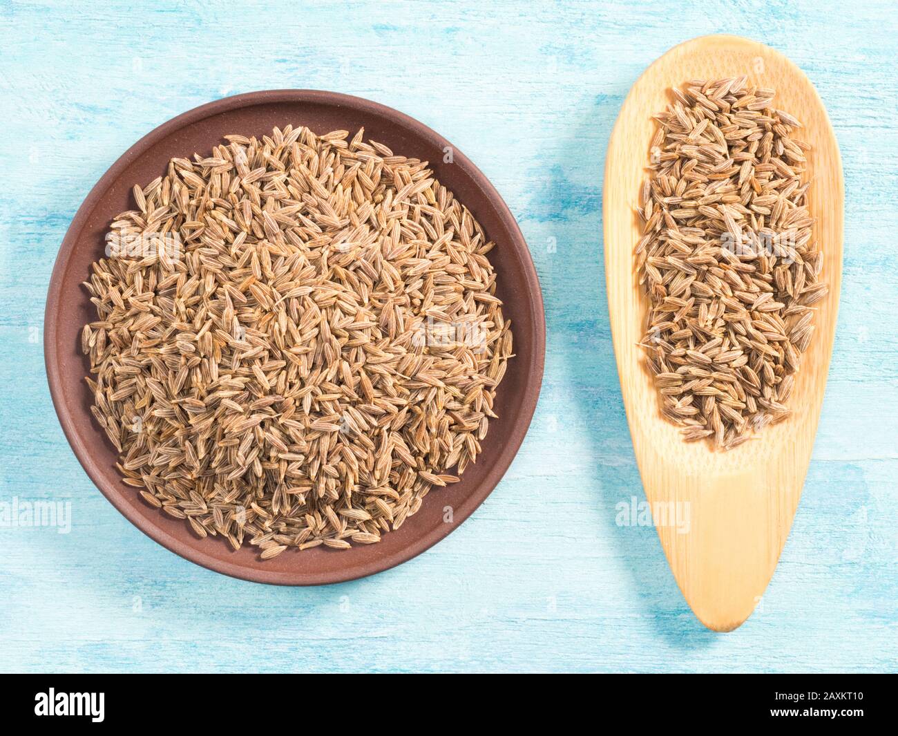 Spice cumin (jeera) in clay plate and wooden spoon on blue wooden ...
