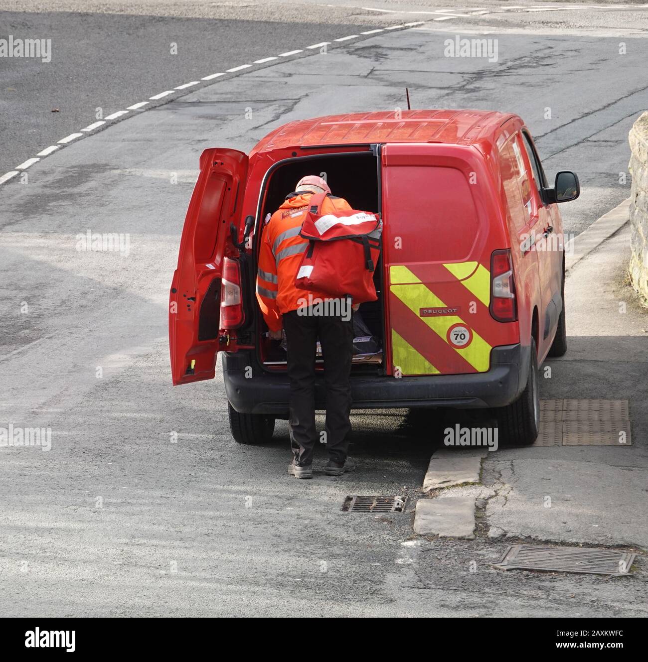 A postman collects his deliveries from the back of his van before his ...
