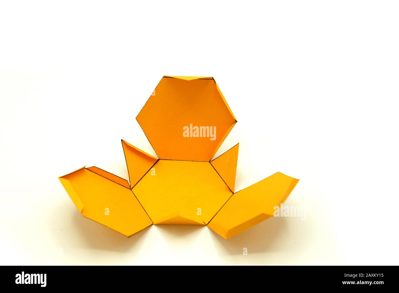 Geometric shape cut out of yellow paper and photographed on white ...