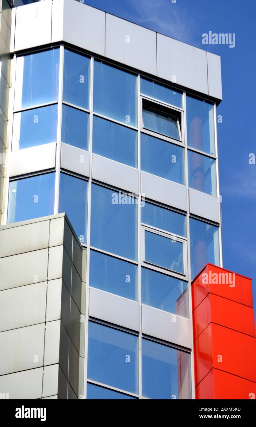 mirrored glass windows of the new building. Blue glass, red and gray ...