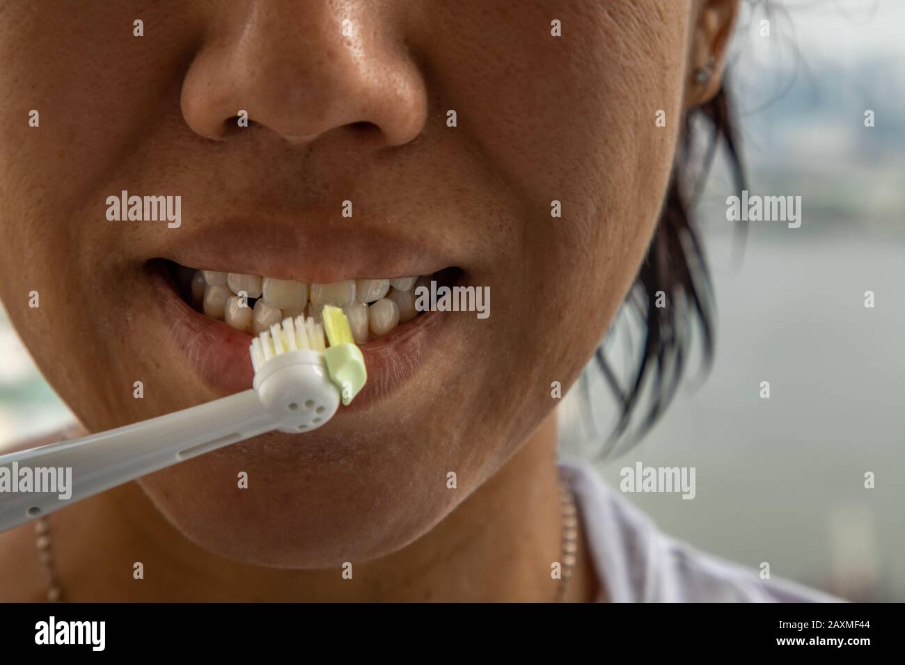 Closeup on young woman brushing teeth with Electric toothbrush on white ...