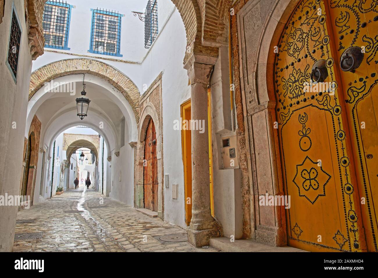 Typical cobbled and narrow street with colorful doors, columns and ...