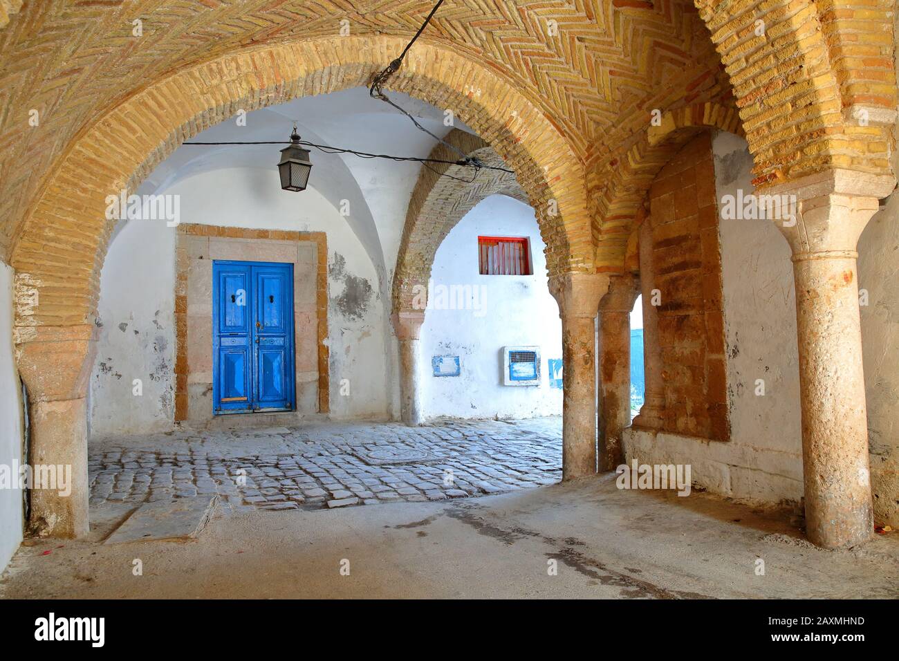 Typical cobbled and narrow street with colorful doors, columns and ...