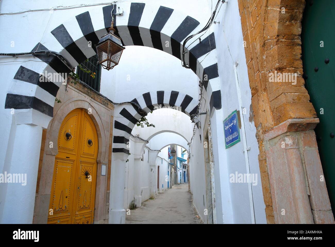 Typical cobbled and narrow street with colorful doors, columns and ...
