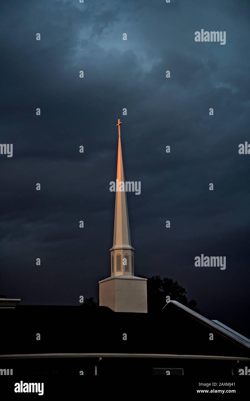 Church Steeple lit up by setting sun against dark rain clouds Stock ...
