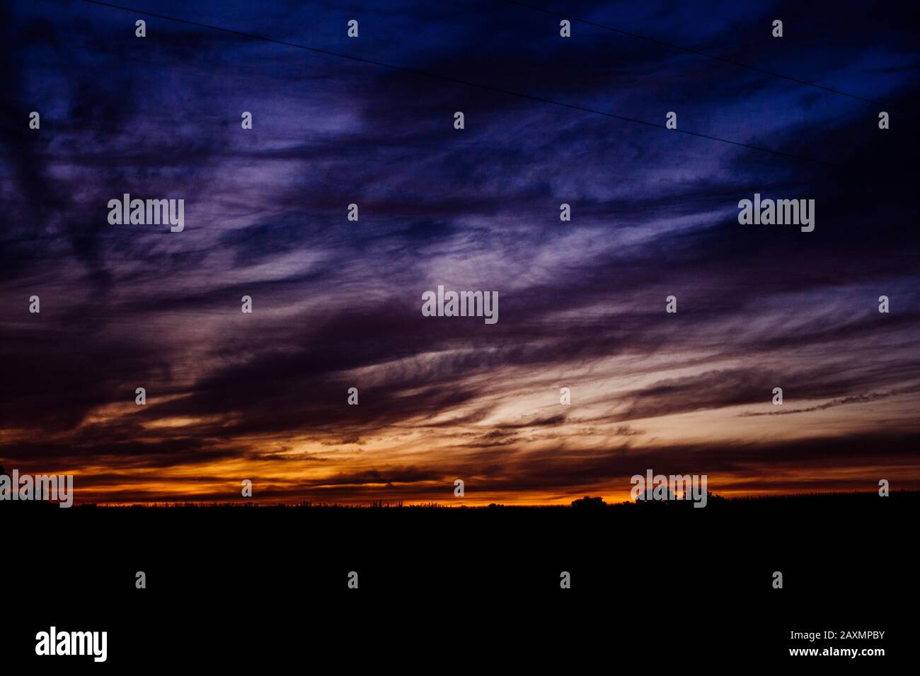 Orange and Purple Sunset with Wispy Black Clouds over a Country Field ...