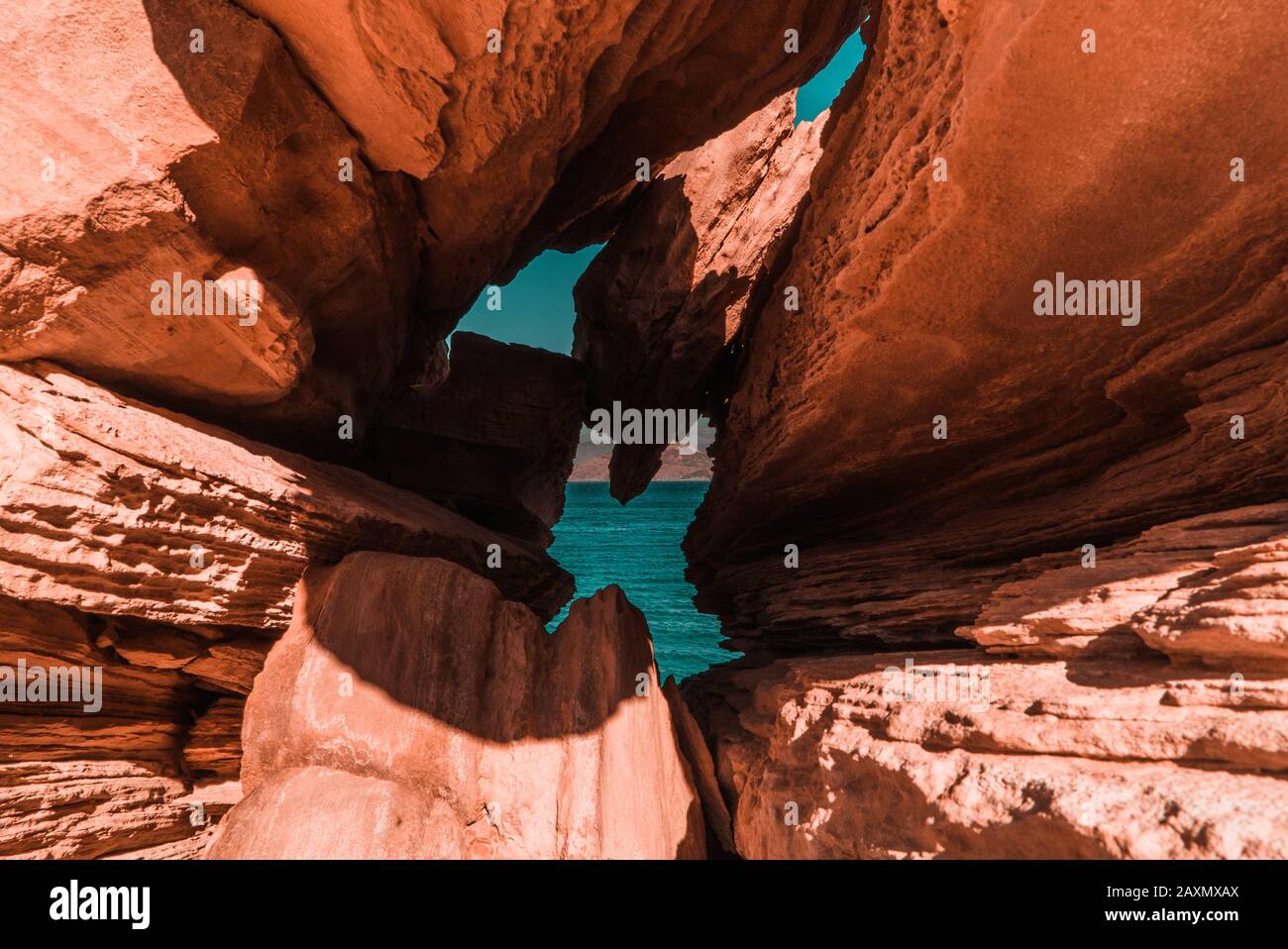 Abstract rocks with view of the ocean between a hole, Triopetra beach ...