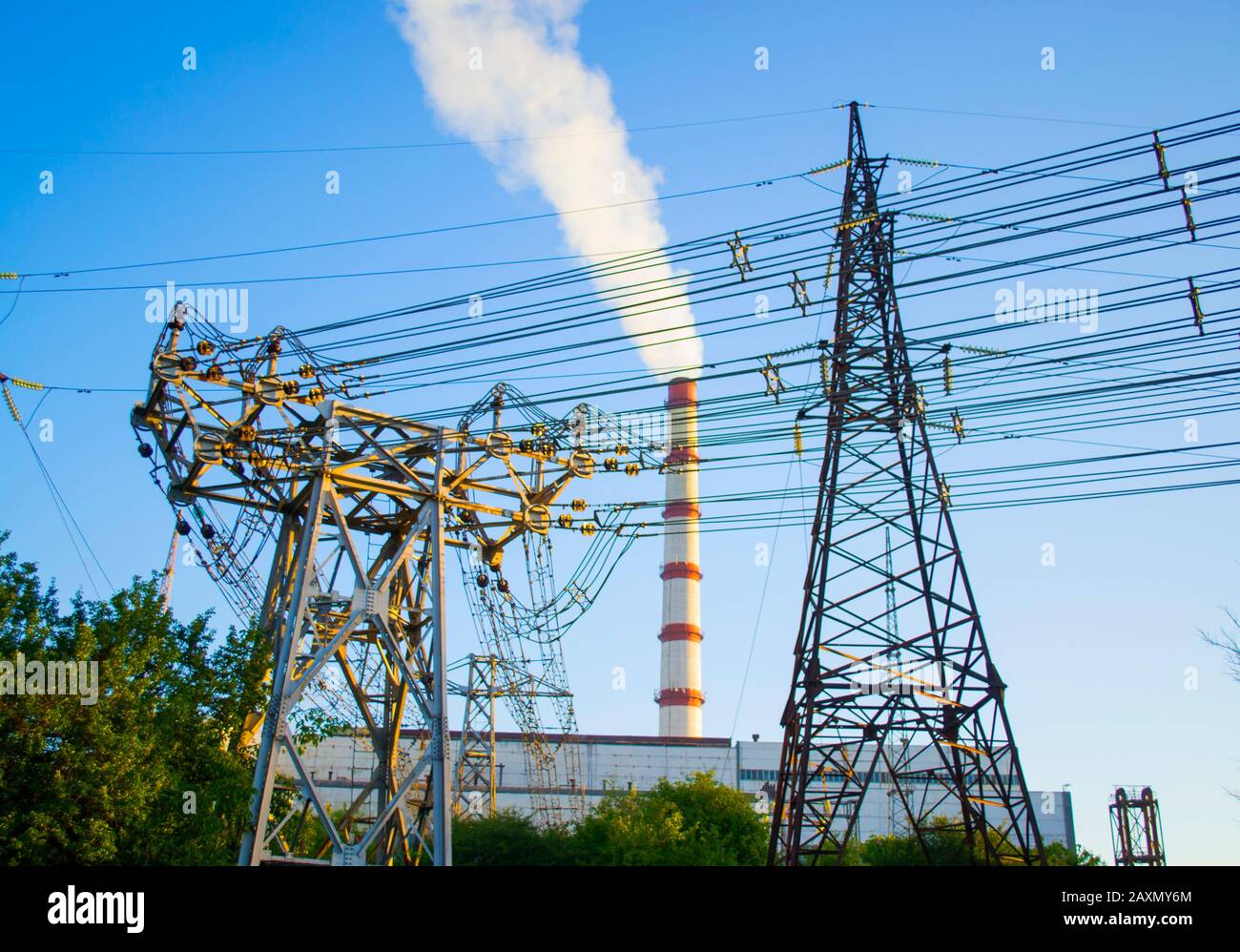 Big power lines and power station chimney in the sunny day with blue ...