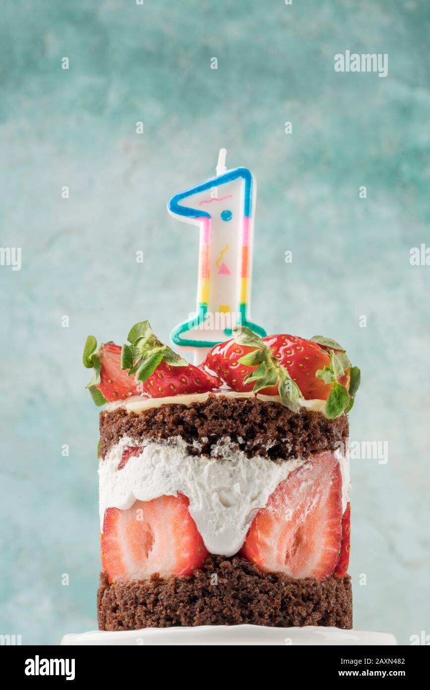 a strawberry cake with number one shaped candle for birthday Stock ...