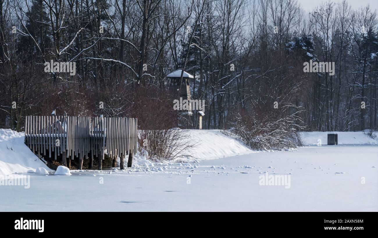 Wooden pier on a frozen lake shore with a hunting observatory in the ...