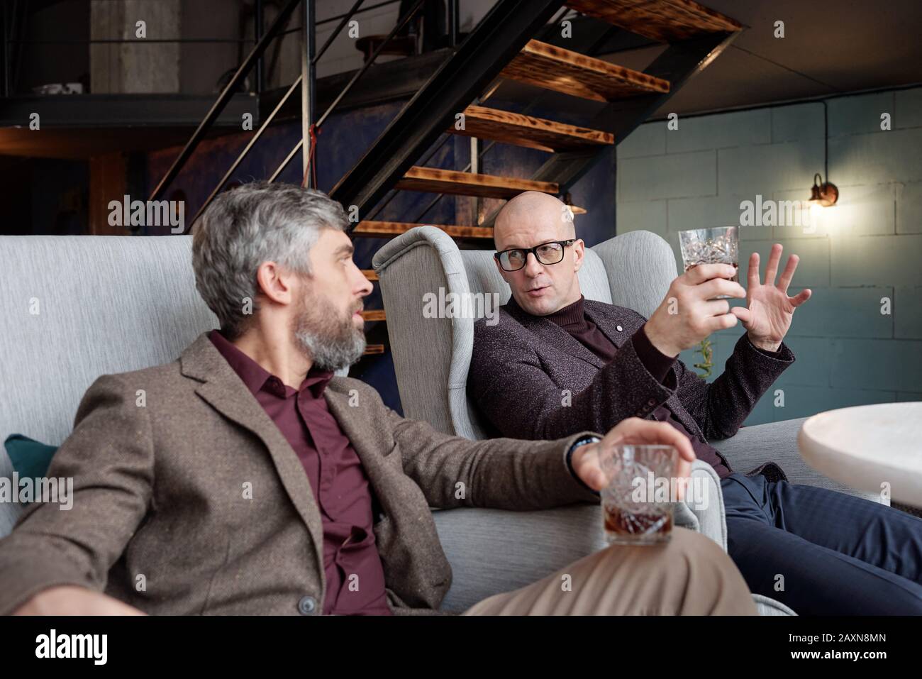 Two middle-aged businessmen drinking whisky in lounge bar and planning ...