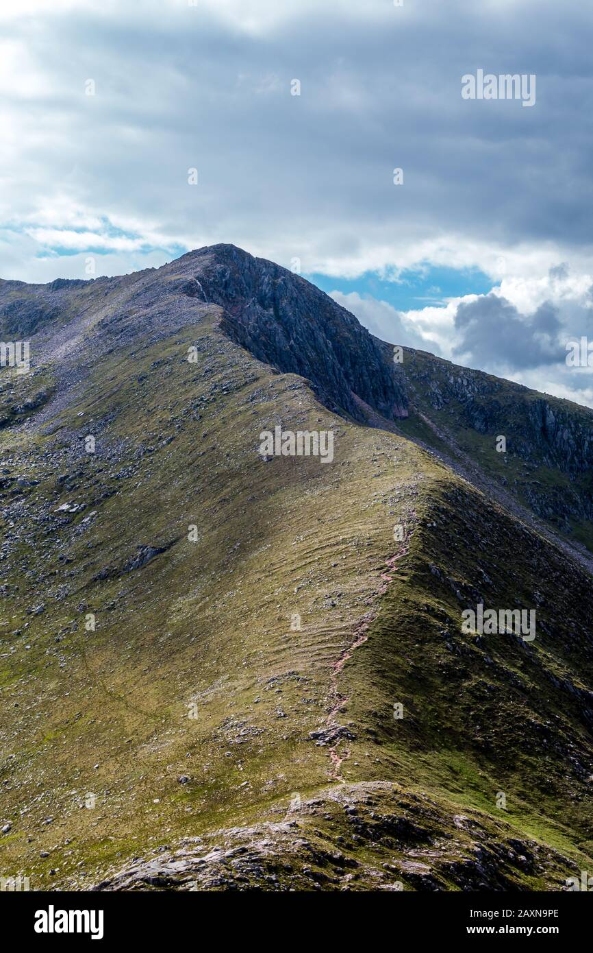 Mountain trail leading along a rocky ridge to Munro peak Beinn nan ...